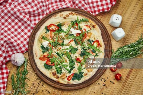 나무 트레이에 필라델피아 치즈 토마토 올리브 아루굴라 새우 화이트 소스를 곁들인 피자 나무 테이블에 재료와 구성 피자 녹기에
