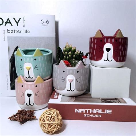 Three Ceramic Cat Planters Sitting On Top Of A Box Next To A Ball Of Yarn