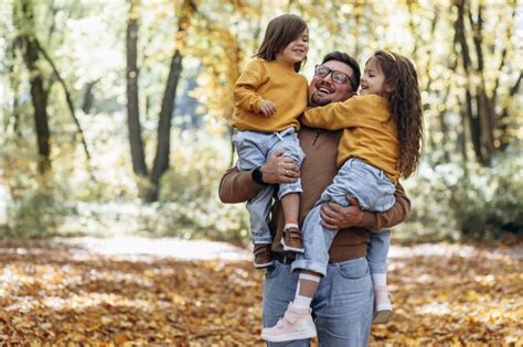 Padre con hijas divirtiéndose en el parque otoñal Foto Premium