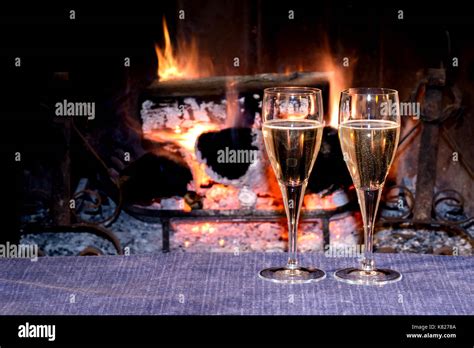 Zwei Gläser Champagner vor dem brennenden Kamin einen romantischen Abend mit Schatz zu feiern