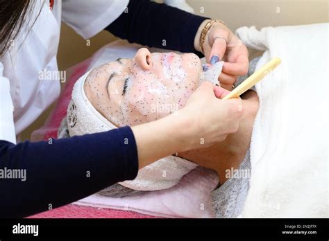 A Beautician Removes A Moisturizing Sheet Mask On A Woman S Face With A Spatula Cosmetology