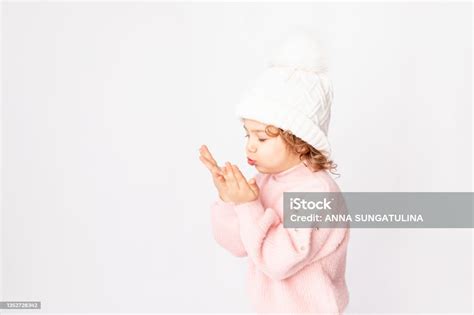 귀여운 아기 소녀 에 핑크 겨울 옷 에 A 흰색 배경 불면 떨어져서 그녀의 손 텍스트 에 대 한 공간 12 13세에 대한 스톡