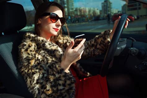 Beautiful Woman In A Fur Coat With Red Lips Using Smartphone In Stock