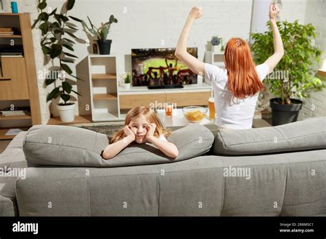 Junge aufgeregte Frau zu Hause auf der Couch sitzt und sich das Fußballspiel im fernsehen