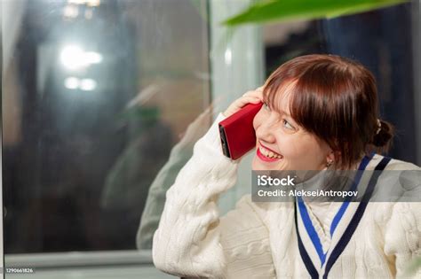 그녀의 손에 스마트 폰과 흰색 스웨터에 예쁜 소녀는 창가에 의해 집의 창턱에 앉아 30 34세에 대한 스톡 사진 및 기타 이미지