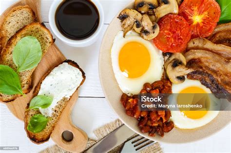 영어 아침 계란 베이컨 토마토 소스 버섯 토마토 콩 크림 치즈와 흰색 나무 바탕에 커피와 토스트 전통적인 영국 요리입니다 최고의