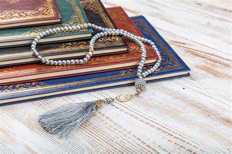 나무 테이블에 걸쳐 알 꾸 란과 Tasbih 또는 묵 주 구슬의 의미 아랍어 서 예와 거룩한 꾸 란 선택적 초점 및 작물 조각