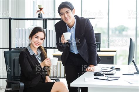 젊은 아시아 사업가와 사업가 파트너는 함께 작업하는 동안 사무실에서 나무 테이블 배경에 컴퓨터와 업무 회의 전에 커피 한 잔을
