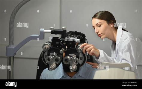 Attentive Ophthalmologist Checking Eye Vision Of Patient With Phoropter