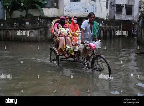 Residents Ride On Rickshaw Through Water Logged Street After Heavy