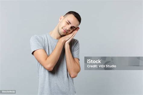 캐주얼 휴식에 젊은 남자를 깜박 얼굴 가까이 손을 자 고 스튜디오에서 회색 배경에 고립 된 눈을 유지 사람들은 진심으로 감정 라이프 스타일 개념입니다 복사 공간을 모의