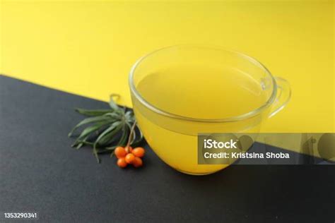 검은 색 노란색 밝은 배경에 바다 갈매 나무 속 차 음료 바다 갈매나무는 바다 갈매나무가 검은 색과 노란색 배경에 오렌지 열매를 잎 바다 갈매 나무의 주물 옆에 유리 컵에