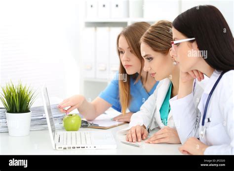 Three Female Doctors Looking At Monitor Medical And Healthcare Concept