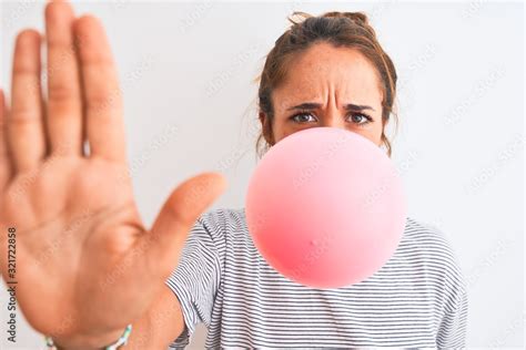 Young Redhead Woman Chewing Gum And Blowing Hair Bubble Over White Isolated Background With Open