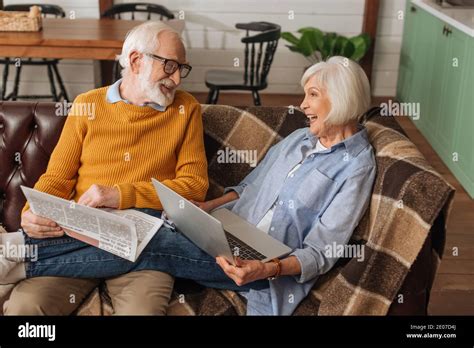 Happy Senior Couple Laughing While Looking At Each Other On Couch In