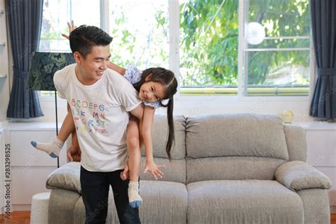Happy Asian Dad Holding His Daughter While He Standing In Living Room