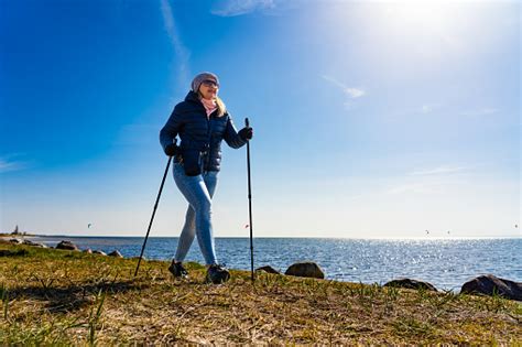 진한 파란색 재킷 청바지 및 겨울 모자를 입고 아름 다운 젊은 여자가 겨울에 화창한 날에 모래 해변을 걷는 북유럽 훈련 앞 View 30 39세에 대한 스톡 사진 및 기타