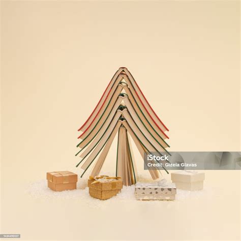 파스텔 베이지색 배경에 격리된 책으로 만든 선물 상자와 크리스마스 트리가 있는 최소한의 추상적인 창의적인 새해 장면 크리스마스 인사말 또는 기프트 카드 교육 개념입니다 책에
