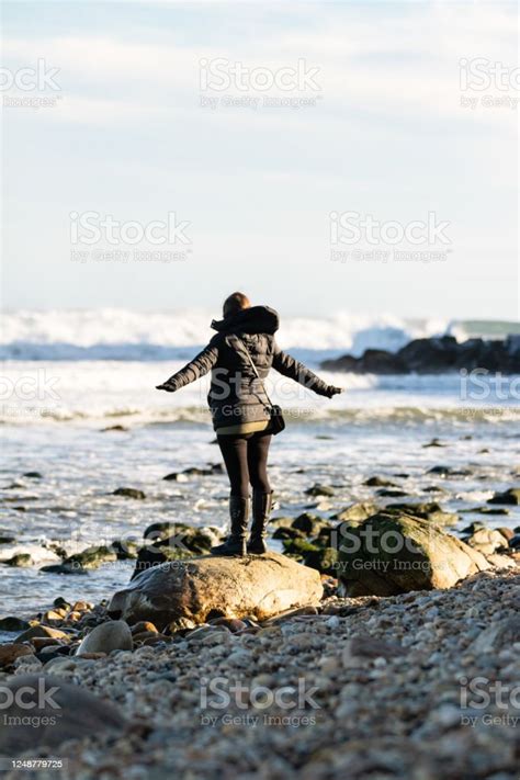 바위 위에 서서 바다를 바라보며 해변에서 포즈를 취하는 젊은 여성 겨울에 대한 스톡 사진 및 기타 이미지 겨울 롱아일랜드