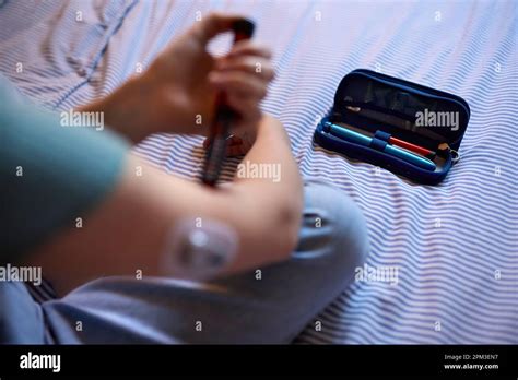 Close Up Of Diabetic Girl On Bed In At Home Using Insulin Pen To Measure To Check Blood Sugar