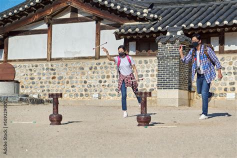 한국의 옛날 전통 가옥에서 마스크를 쓰고 민속놀이를 즐기는 젊은 아시아 한국 커플 모델 Stock 写真 Adobe Stock