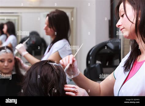 Hairdresser Applying Color To Female Customer At Hair Salon Woman Having Her Hair Dyed Stock