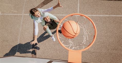 아버지와 십대 딸이 코트에서 밖에서 농구를 하고 있고 후프 네트 위의 높은 각도 보기 아버지와 십대 딸이 코트에서 밖에서 농구를 하고 있고 후프 네트 위의 높은 각도