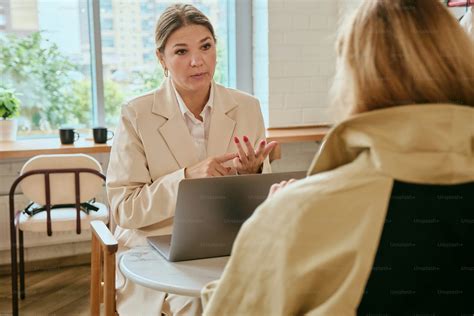 테이블에 앉아 다른 여성과 이야기하는 여성 사진 Unsplash의 출장 이미지