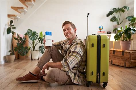 Ein lächelnder hübscher kerl schaut auf seinen reisepass und sein