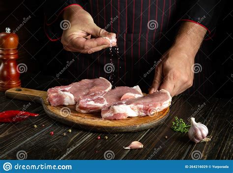 Professional Chef Salts Raw Sliced Meat Steaks On The Cutting Board Of