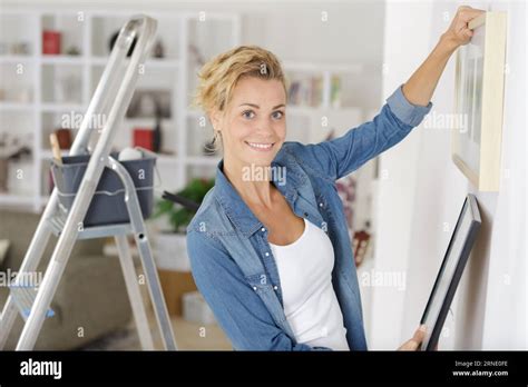 Woman Putting Frame On The Wall Stock Photo Alamy