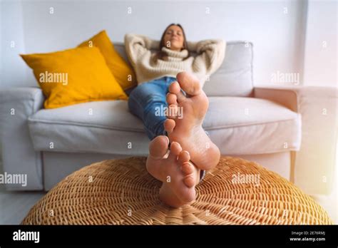 Woman Relaxing On The Sofa With Her Eyes Closed And Hands Behind Her