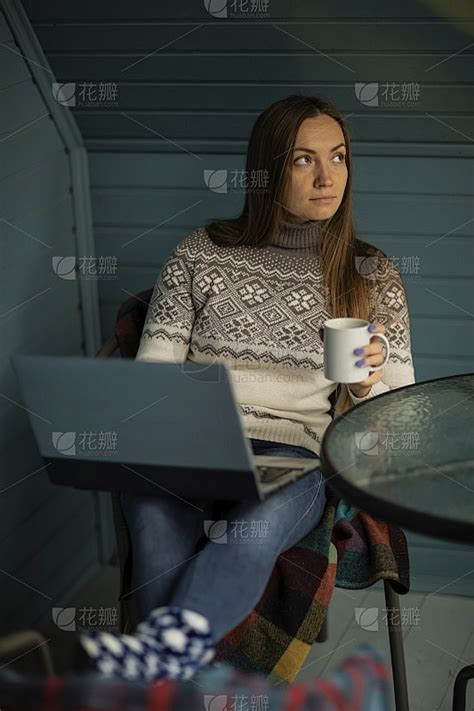 一个年轻女子坐在阳台上手提电脑