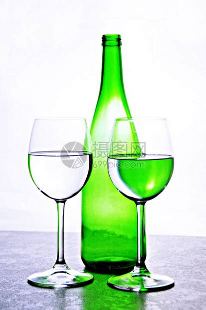 两个带水的酒杯以完全相反的方向反射背景中的绿色酒瓶高清图片下载 正版图片506146857 摄图网