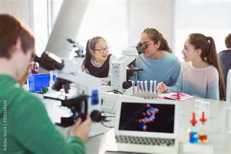 Girl Students Using Microscope Conducting Scientific Experiment In Laboratory Classroom Stock