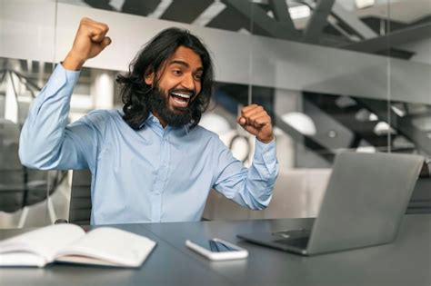Premium Photo Emotional Indian Guy Entrepreneur Looking At Laptop Screen And Gesturing