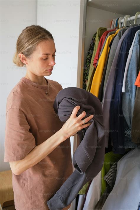 옷 선반 앞에서 천을 들고 있는 여자 사진 Unsplash의 중고 옷 이미지