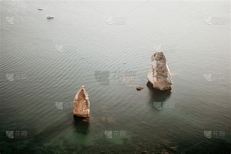从上面俯瞰平静蔚蓝的大海和火山岩石海岸。水面上移动的小波浪模糊了。自然夏季海洋海洋海滩的背景。没有人