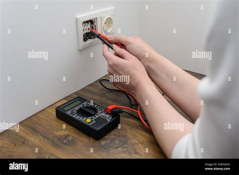Woman Using Digital Multimeter To Check Current Voltage In Electric Socket Stock Photo Alamy