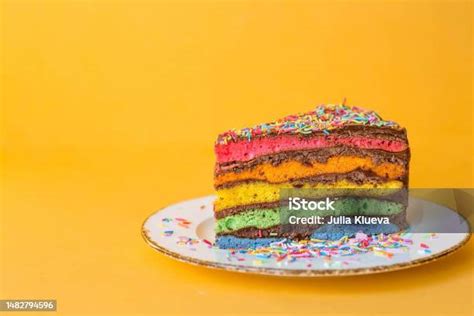 축제 촛불과 색종이로 장식 된 무지개 생일 케이크 과자 노란색 배경에 무지개 색상의 여러 가지 빛깔의 디저트 0명에 대한 스톡