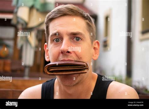 Young Handsome White Man With Brown Hair With Wallet In His Mouth On