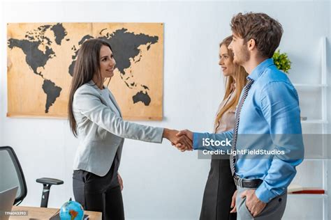 여자 친구 근처에 서있는 행복한 남자와 악수하는 미소 여행사 악수에 대한 스톡 사진 및 기타 이미지 악수 지구본 3 명 Istock