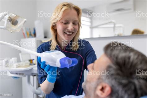 얼룩과 변색을 제거하기 위해 레이저 치아 미백 치료를 받는 남자의 모습을 클로즈업합니다 치과 의사 클리닉에서 치아 표백 2명에