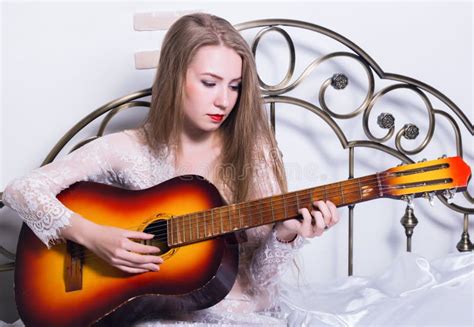 Beautiful Young Woman Playing Music On A Bed With Happiness And Guitar