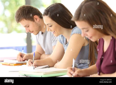 Three Students Studying Taking Notes During A Class In A Classroom