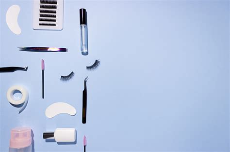 파란색 배경의 속눈썹 확장을위한 도구 인공 속눈썹 자기 관리 핀셋 접착제 및 래쉬 메이커 작업을위한 다른 도구 맨 위 보기 카피 스페이스 가짜 속눈썹에 대한 스톡 사진 및