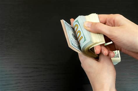 여성의 손은 복사 공간과 어두운 배경 클로즈업에 백 달러 지폐의 스택을 통해 이동 100에 대한 스톡 사진 및 기타 이미지