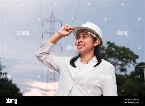 Asian Female Electrical Engineer Working Near High Voltage Pole Inspecting Power Grid Wind