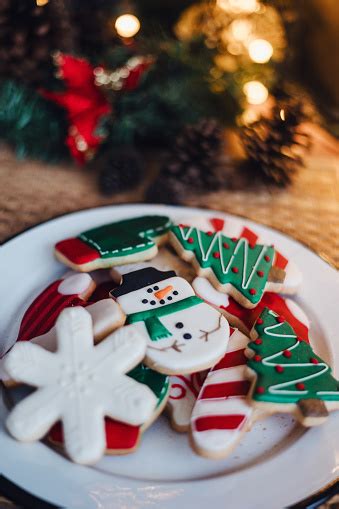 소박한 테이블에 황금색 조명이 있는 시트 또는 접시에 크리스마스 쿠키 전통적인 눈사람 나무 별 쿠키 및 산타 모자를 굽습니다 0명에 대한 스톡 사진 및 기타 이미지 Istock