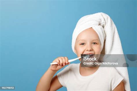 파란색 배경에 어린 소녀의 클로즈업 초상화 머리에 하얀 수건을 두드리로 닦는 아이 매일 위생의 개념 소녀에 대한 스톡 사진 및